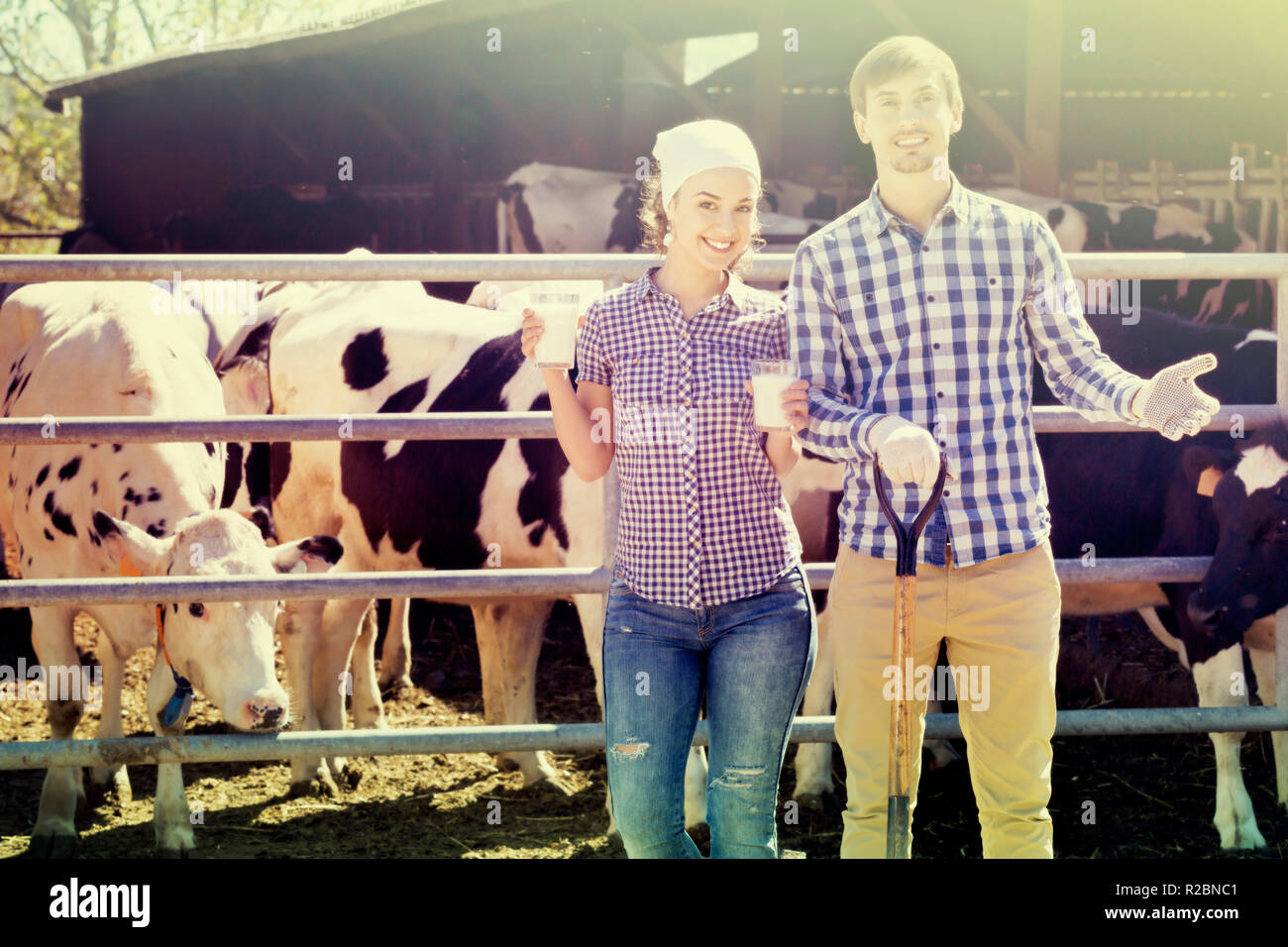 Portrait of two young satisfied smiling farm workers holding glass with ...