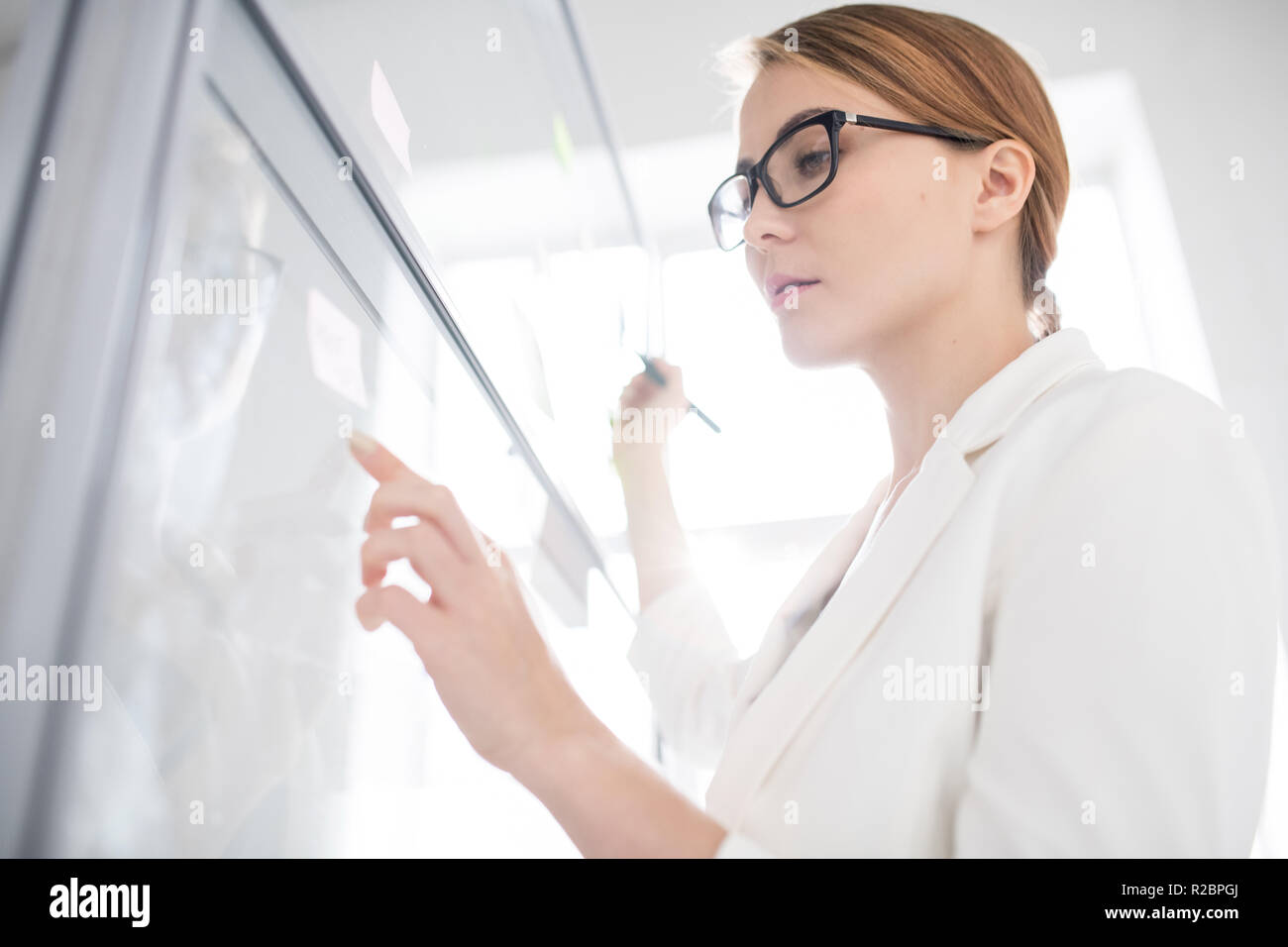 Serious businesswoman drawing on whiteboard Stock Photo - Alamy