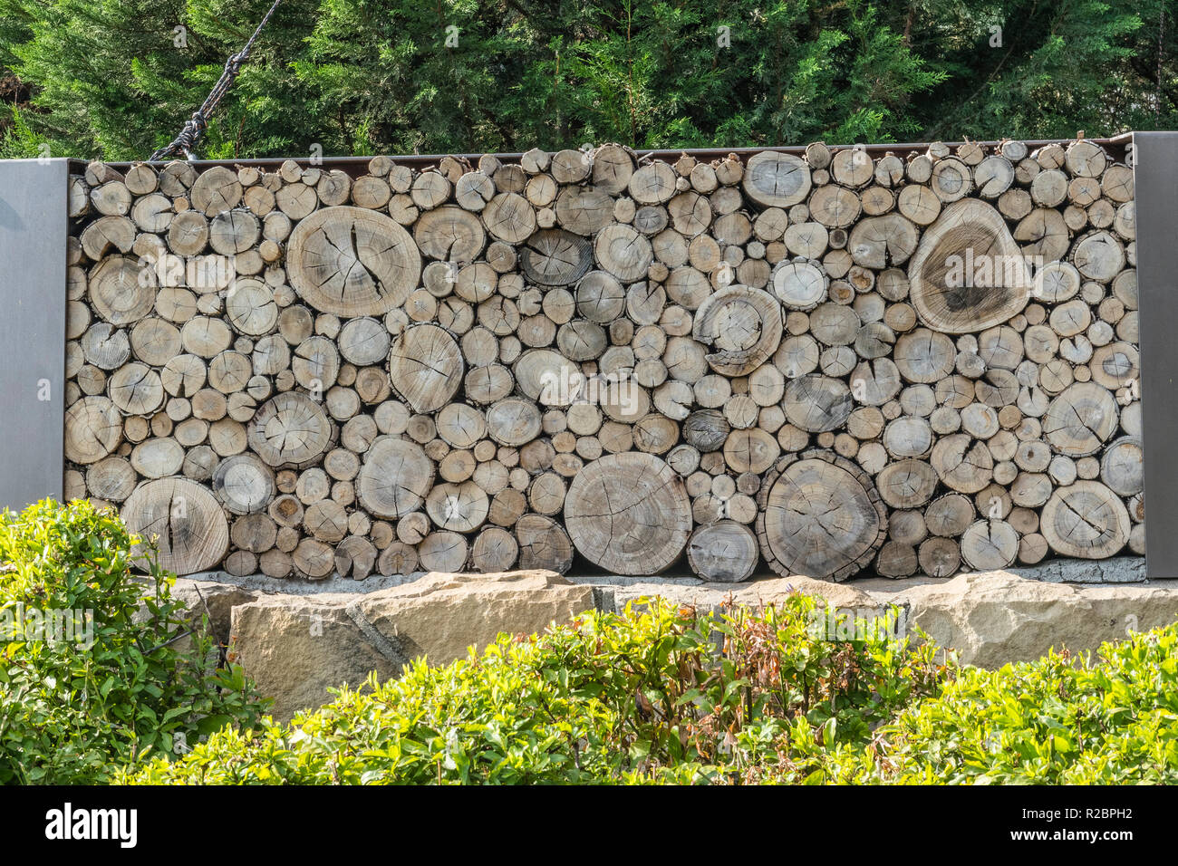 Cut tree trunk and branch wall made up of horizontal logs creating a ...