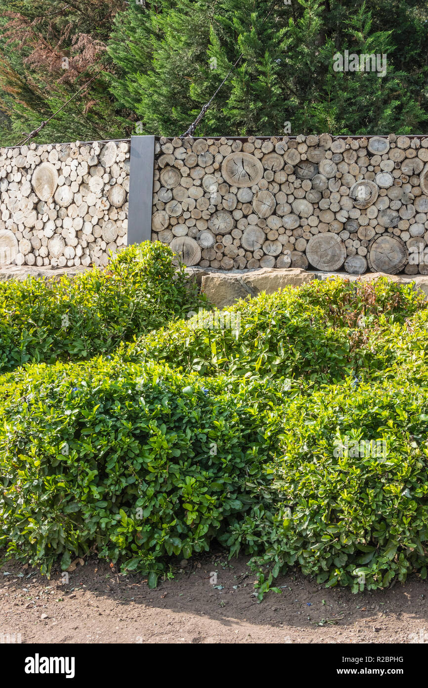 Cut tree trunk and branch wall made up of horizontal logs creating a ...