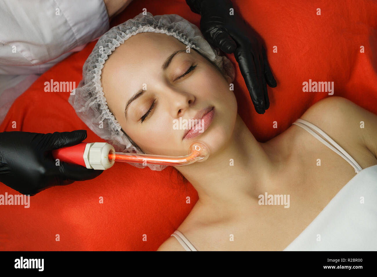 Hardware cosmetology. Beautician Violet ray face of a young woman. Skin ...