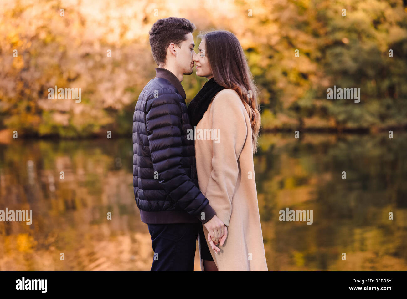 Couple in love standing in autumn park with yellow fallen leaves. Man ...