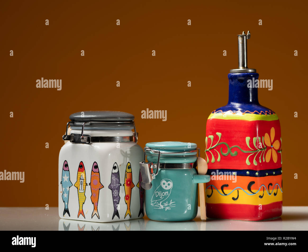 Closeup of two mustard pots with wooden spoons and a red painted bottle ...