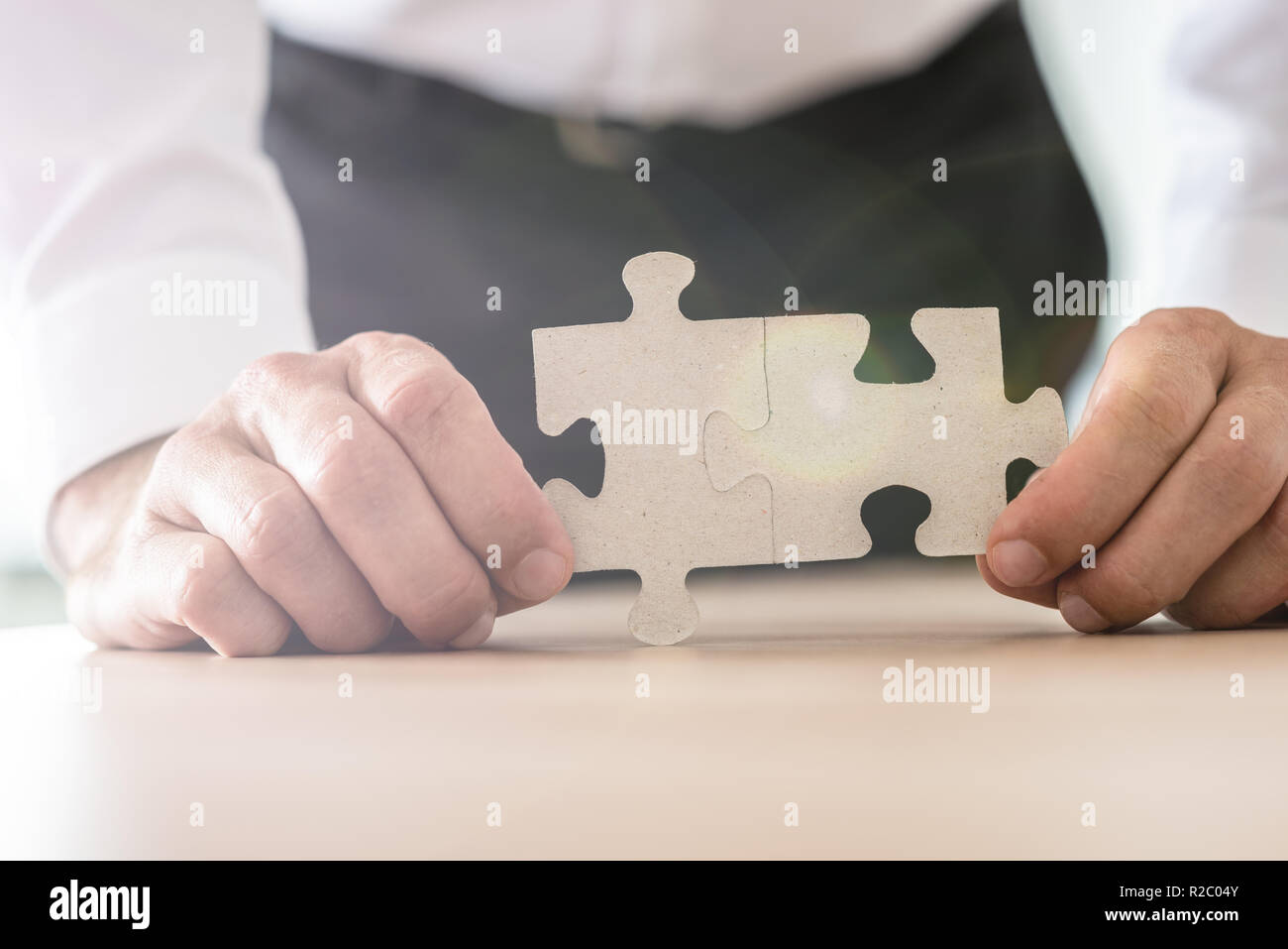 Closeup view of businessman holding two joined puzzle pieces leaning on ...