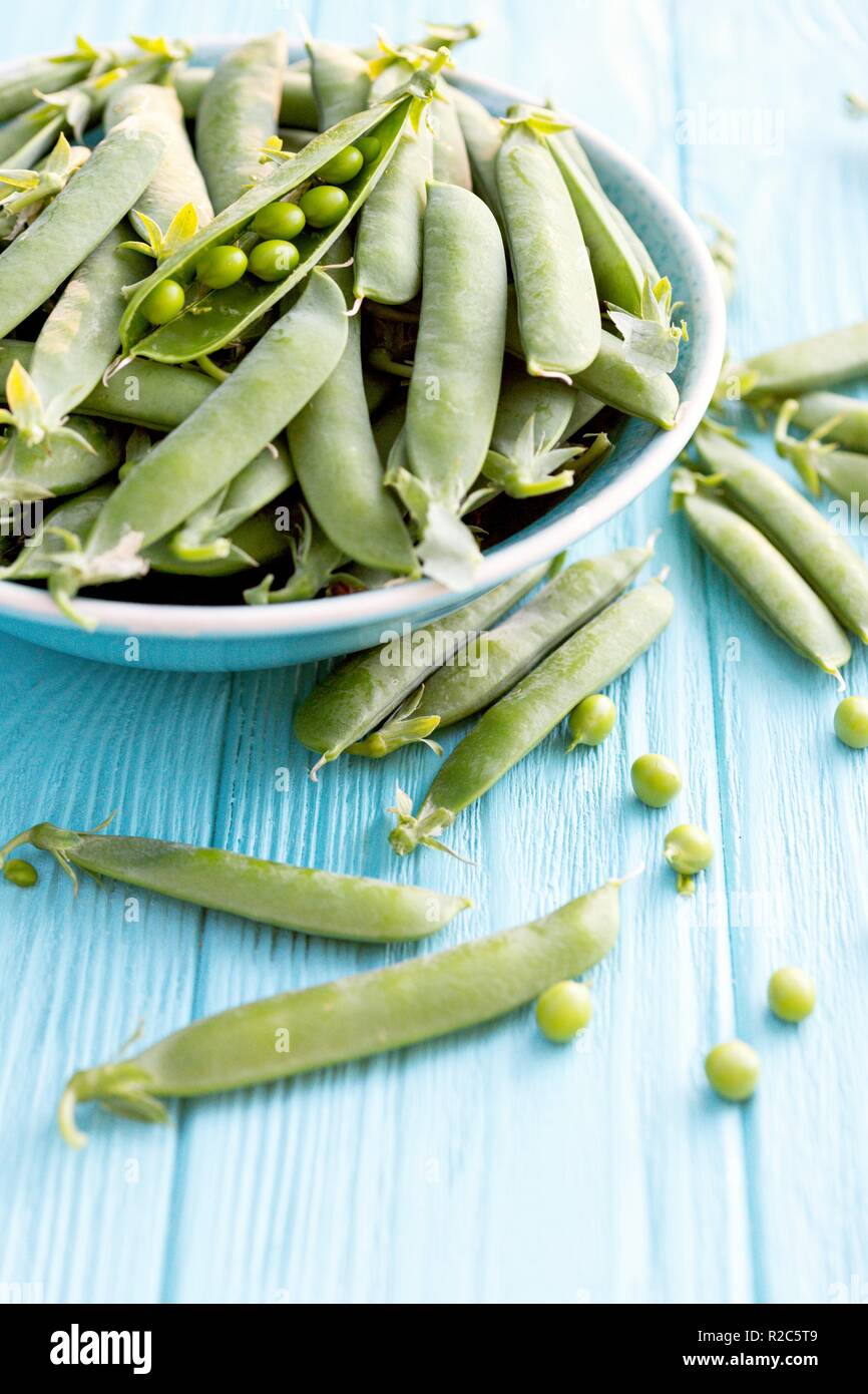 Green peas in pods on a wooden table in the garden at sunset light ...