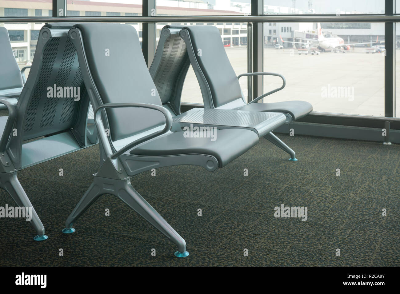 row of gray seats at airport terminal Stock Photo - Alamy