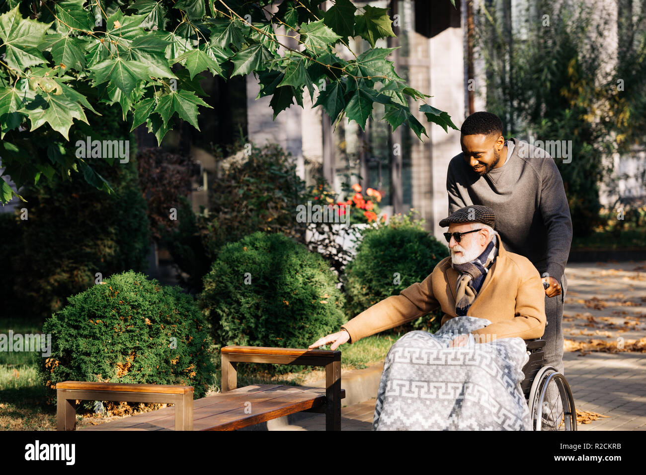 happy senior disabled man in wheelchair and african american cuidador ...