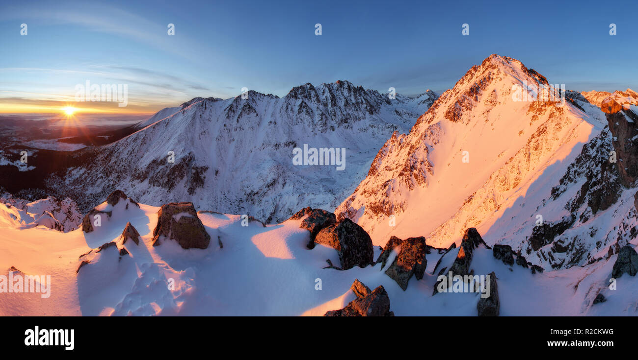 Snowy mountains under orange sunset sky Stock Photo - Alamy