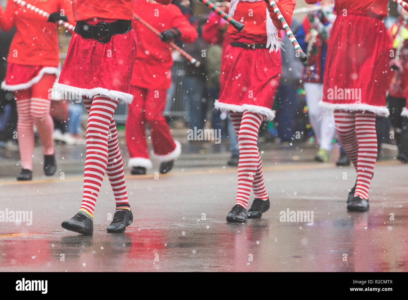 A color guard group dressed in striped tights march in a holiday parade ...