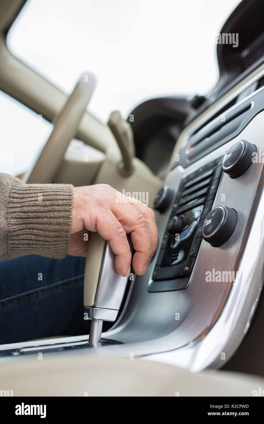 Senior man driving his modern car, going in reverse, watching out not ...