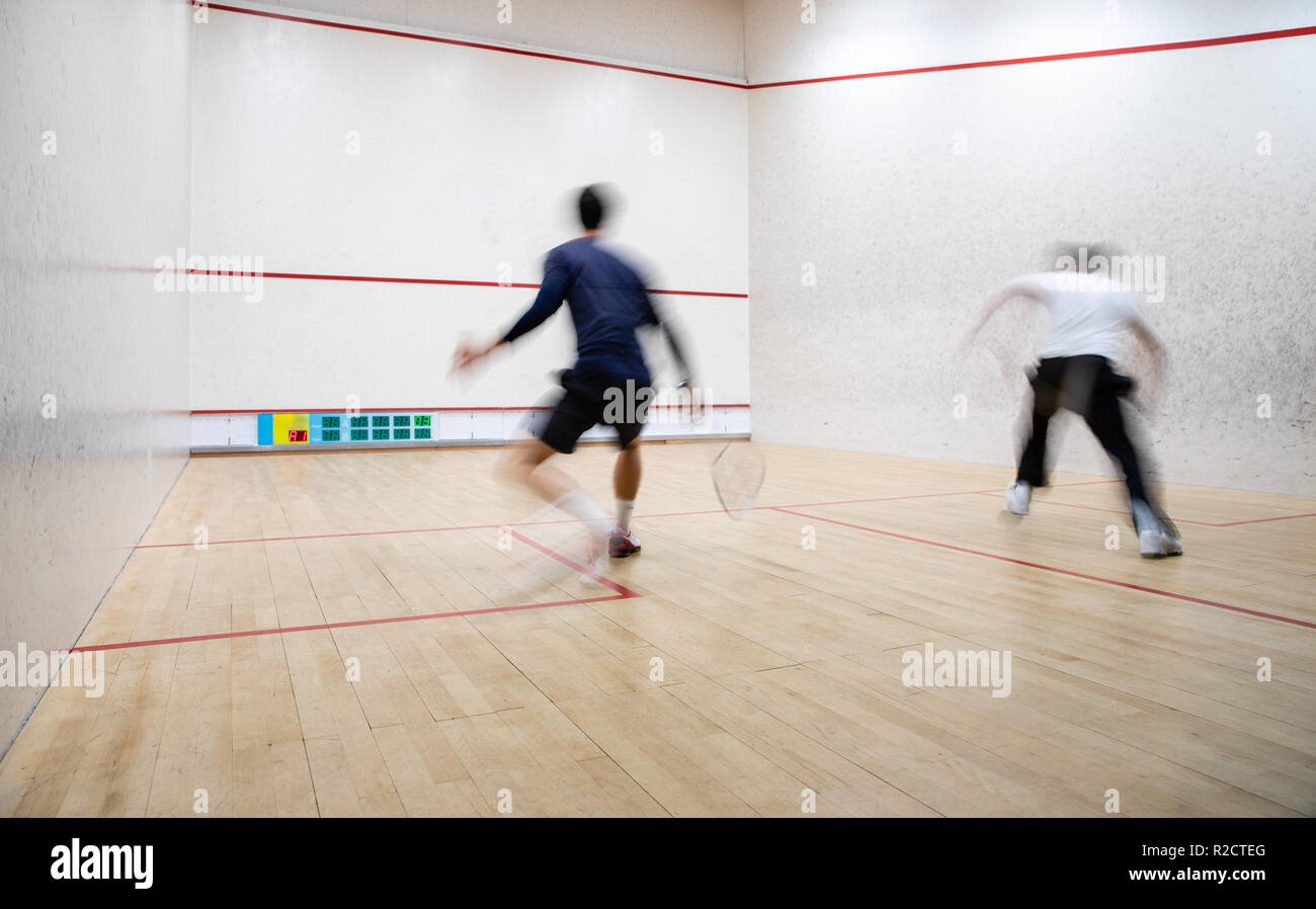 Squash players in action on a squash court (motion blurred image; color ...