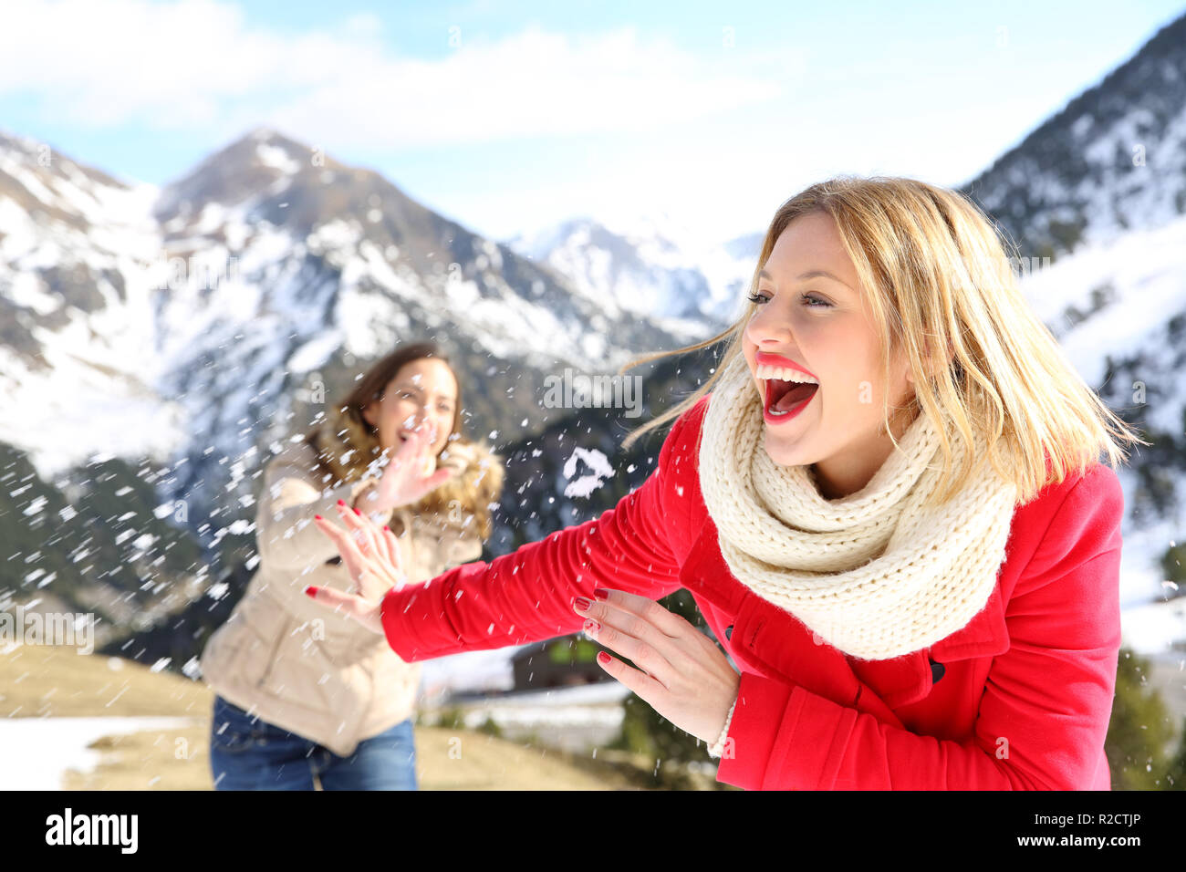 Two funny friends joking throwing snowballs in the mountain on winter ...