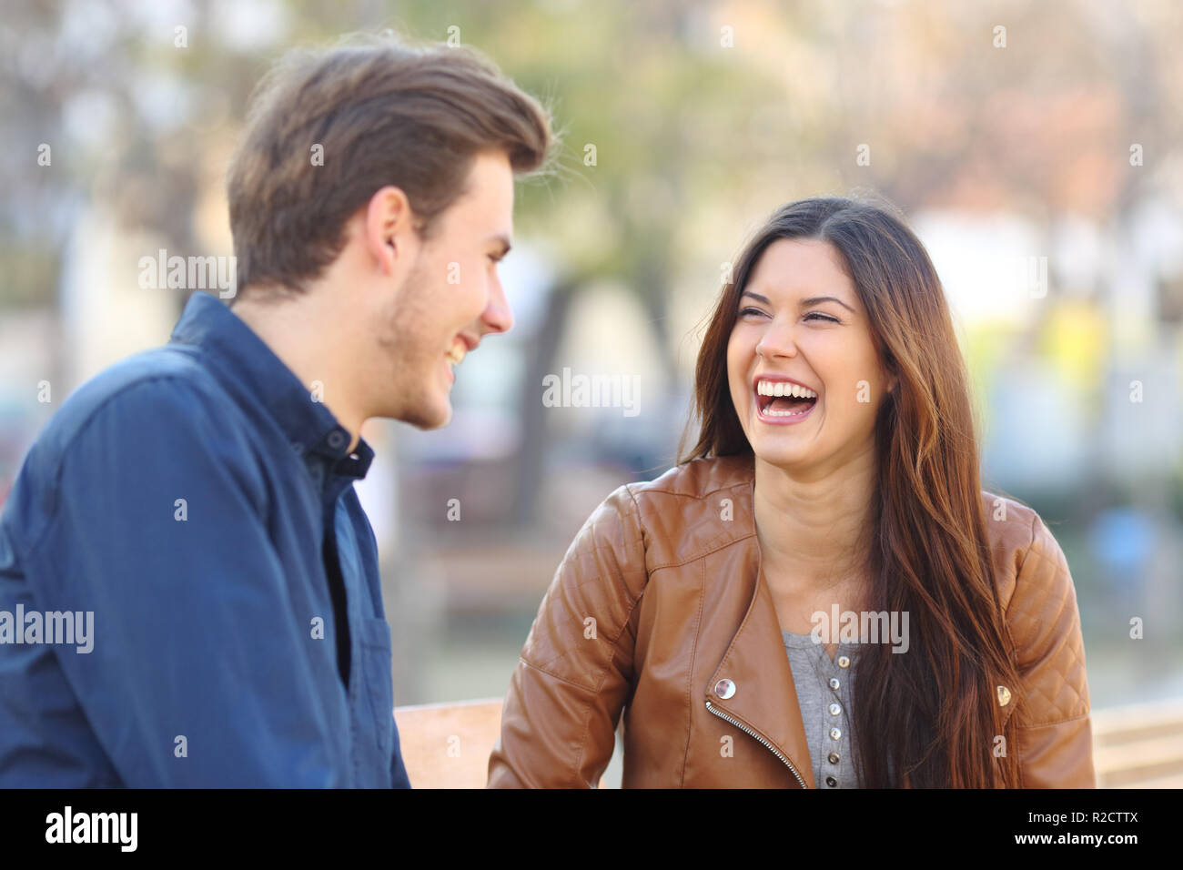 Funny couple laughing together looking each other in the street Stock ...