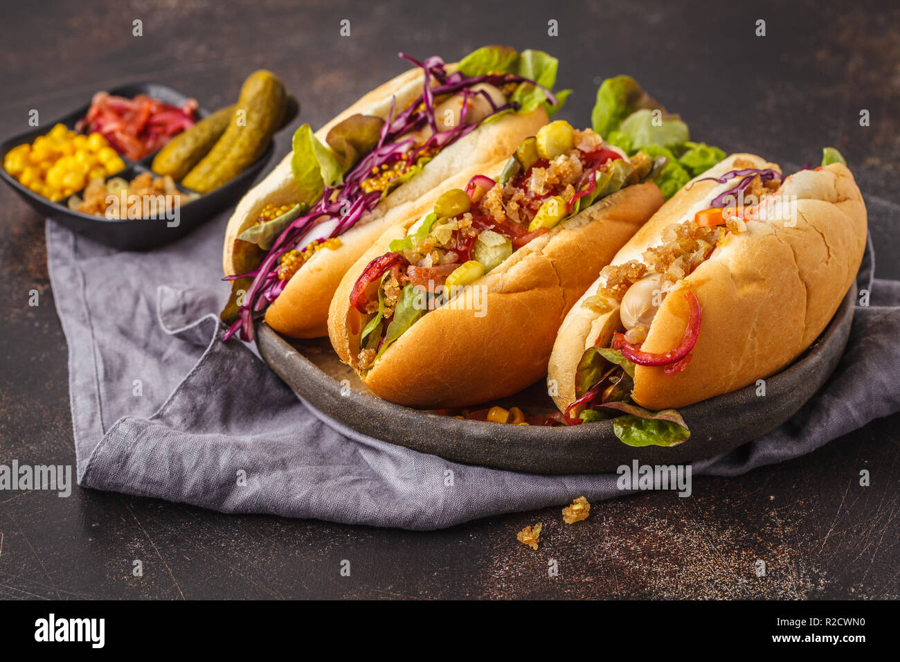 Hot dogs with assorted toppings on a dark background, top view ...