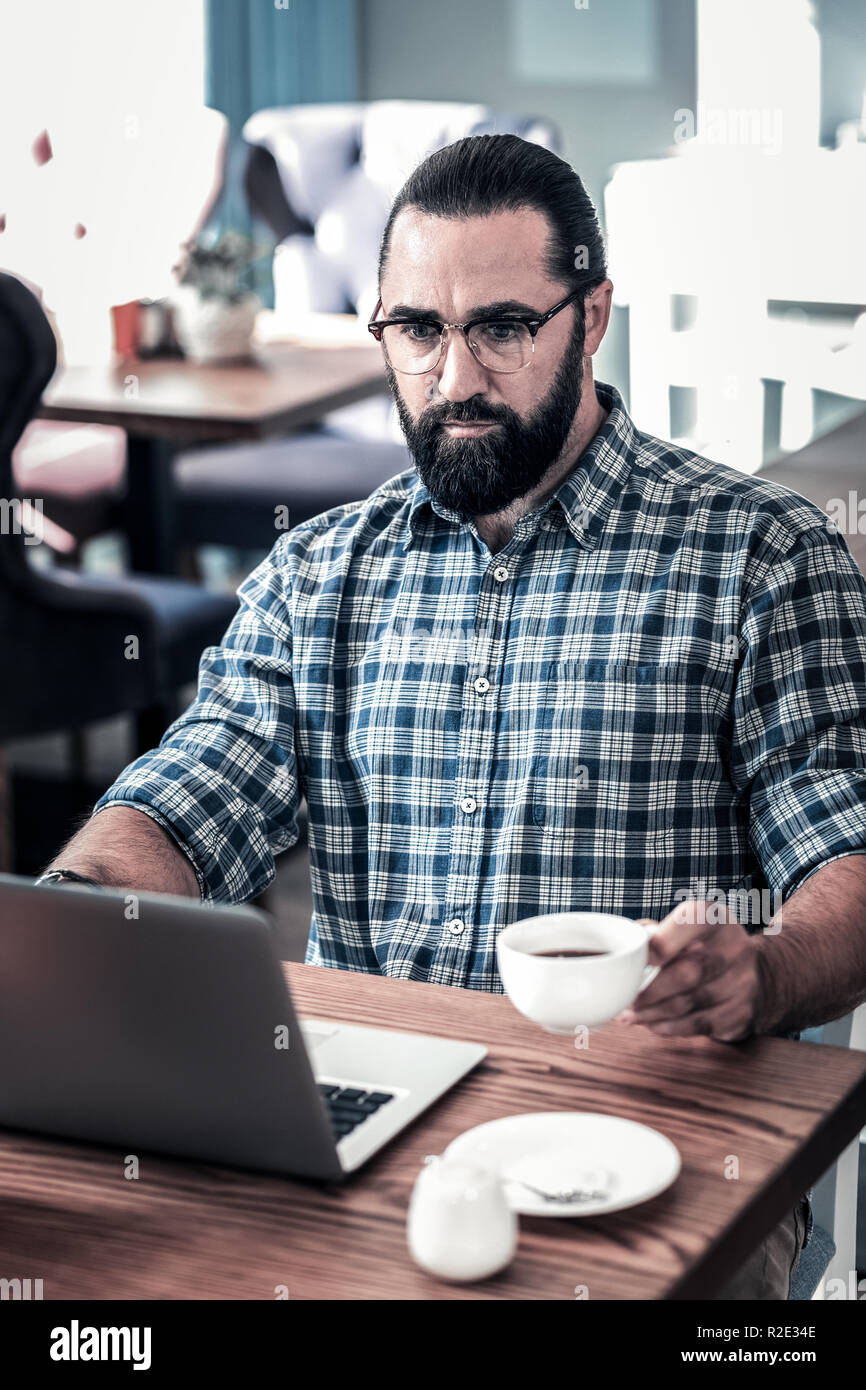 Bearded writer feeling serious while checking his article for magazine ...