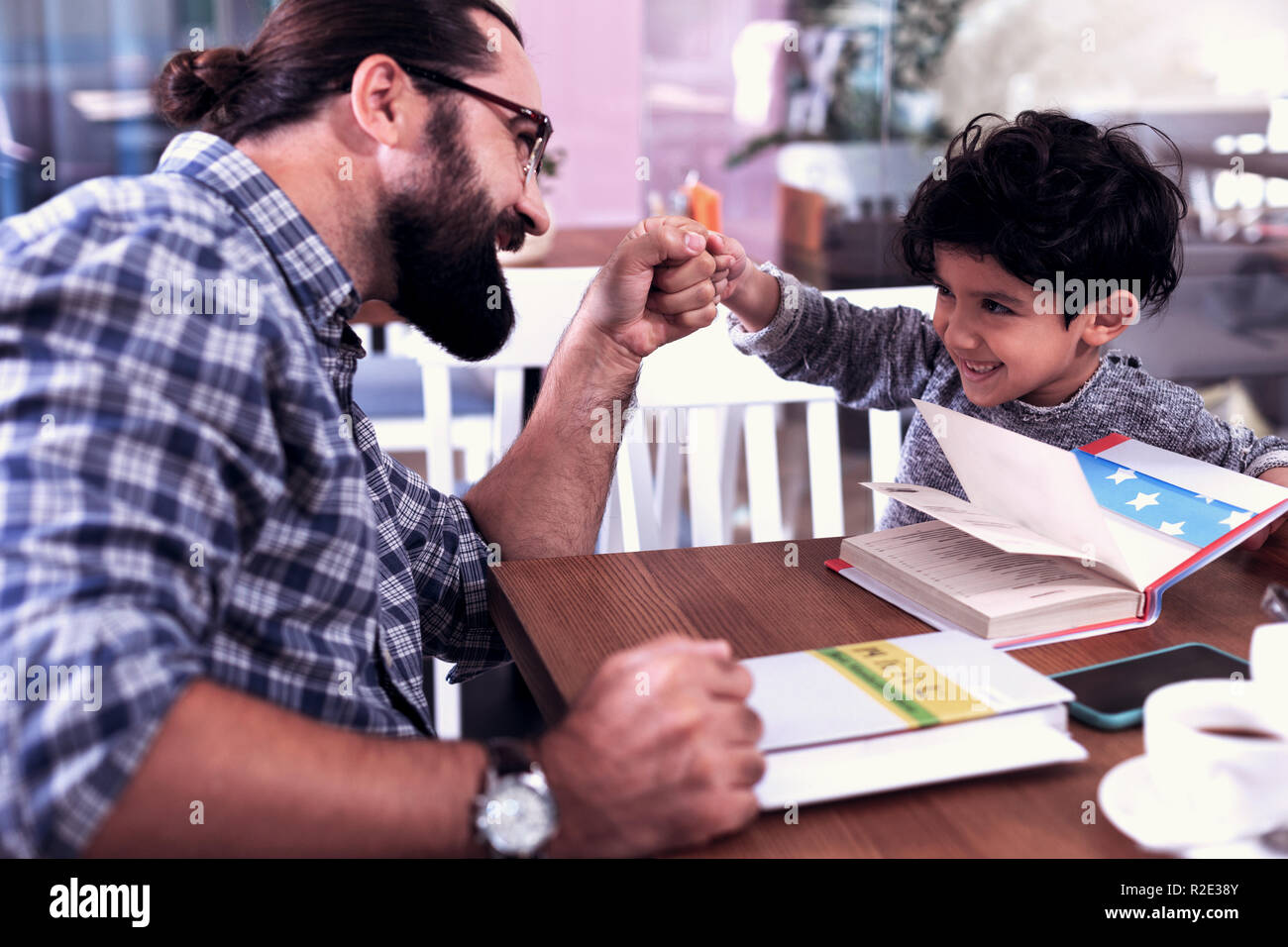 Cheerful cute dark-eyed son feeling amazing having fun with his father ...