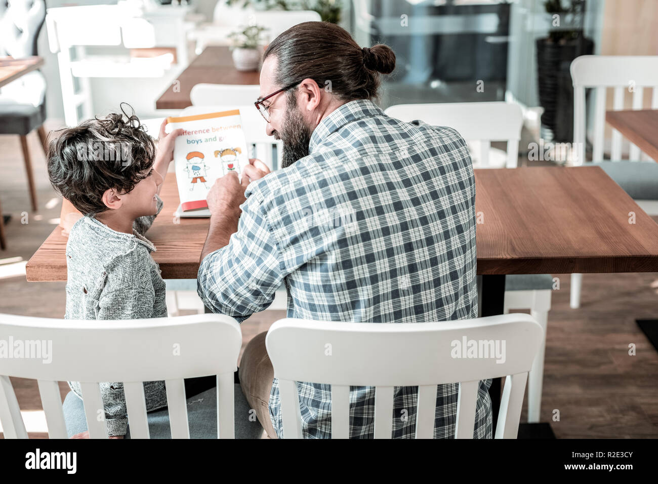 Cute dark-haired son feeling interested while studying with father ...