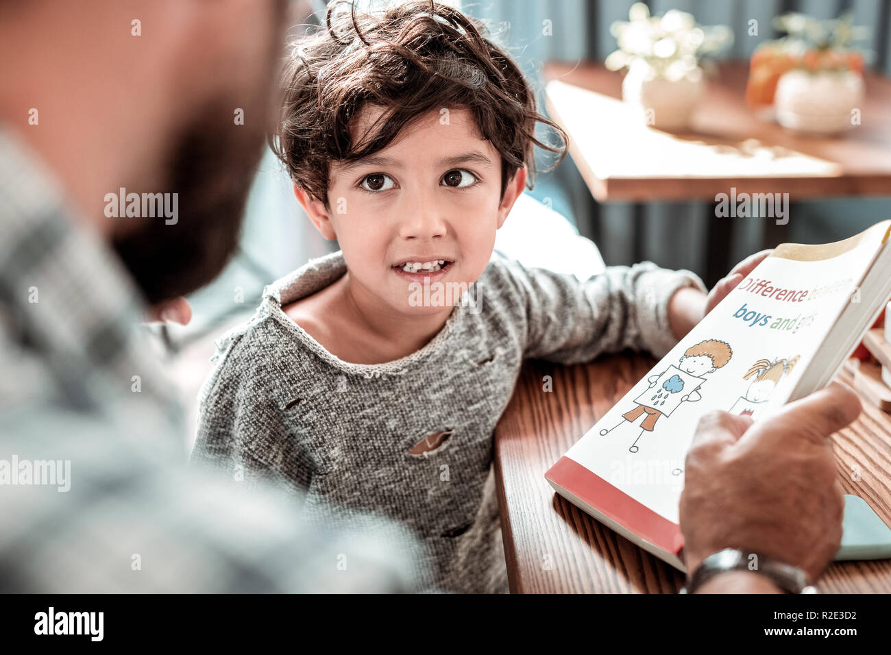 Funny cute boy feeling concerned while studying reading with father ...