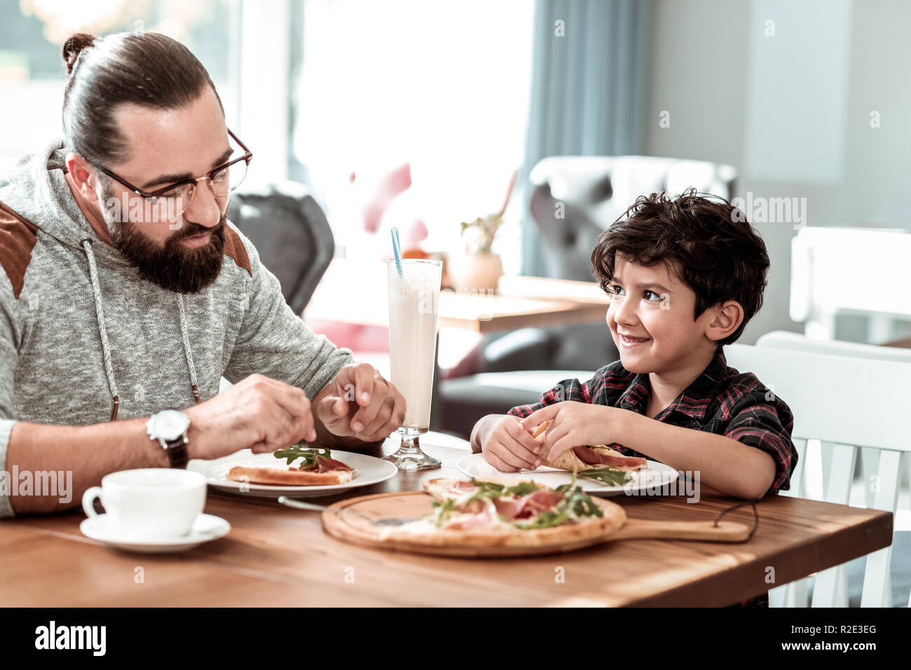 Father and son eating extremely yummy pizza with bacon and cheese Stock ...