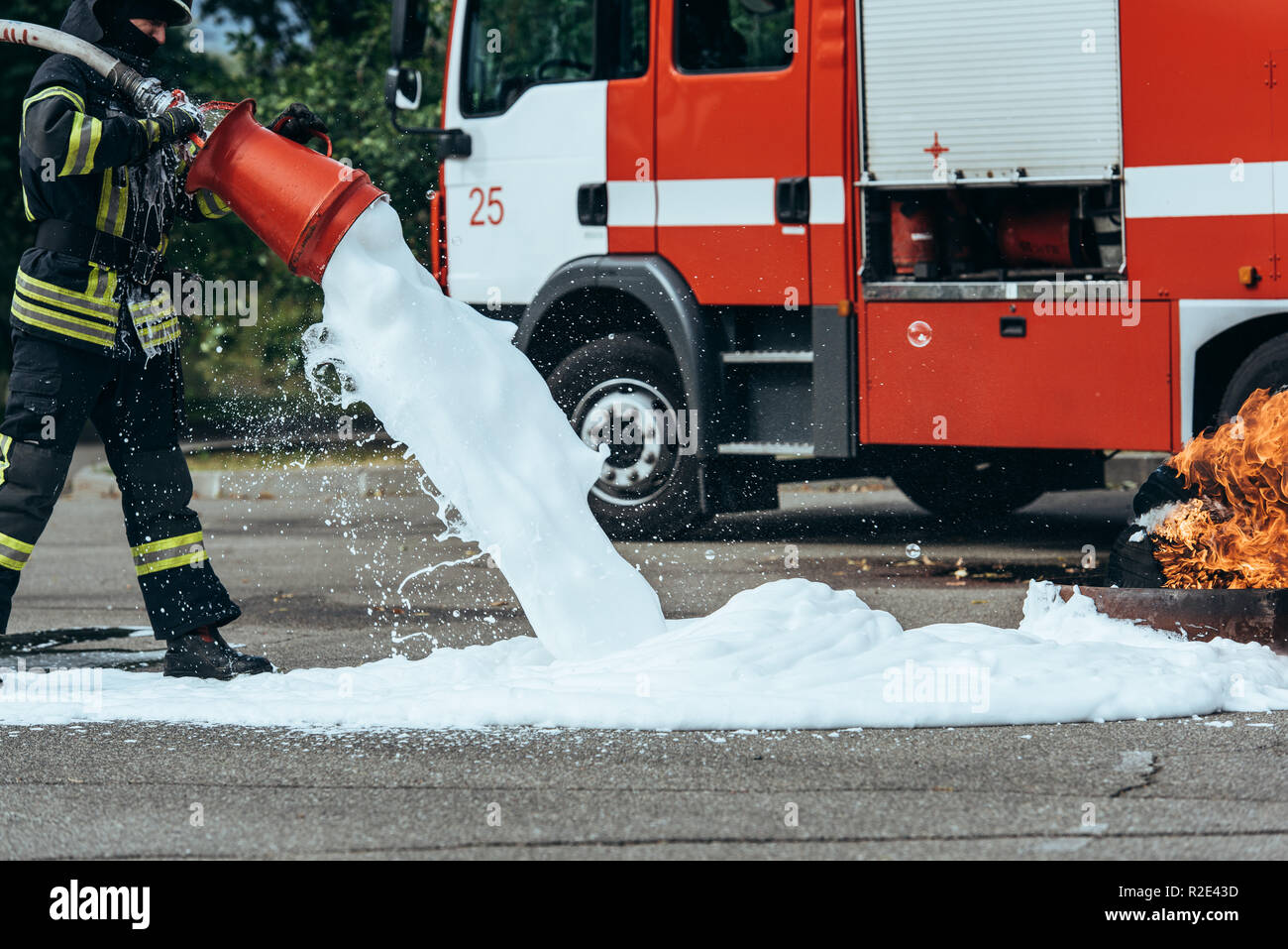 partial view of firefighter extinguishing fire with foam on street ...