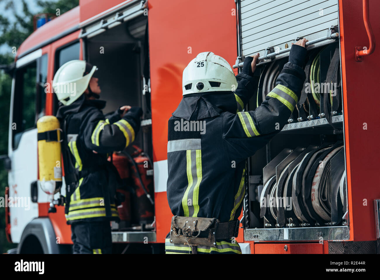 firefighters in protective uniform checking equipment in truck on ...