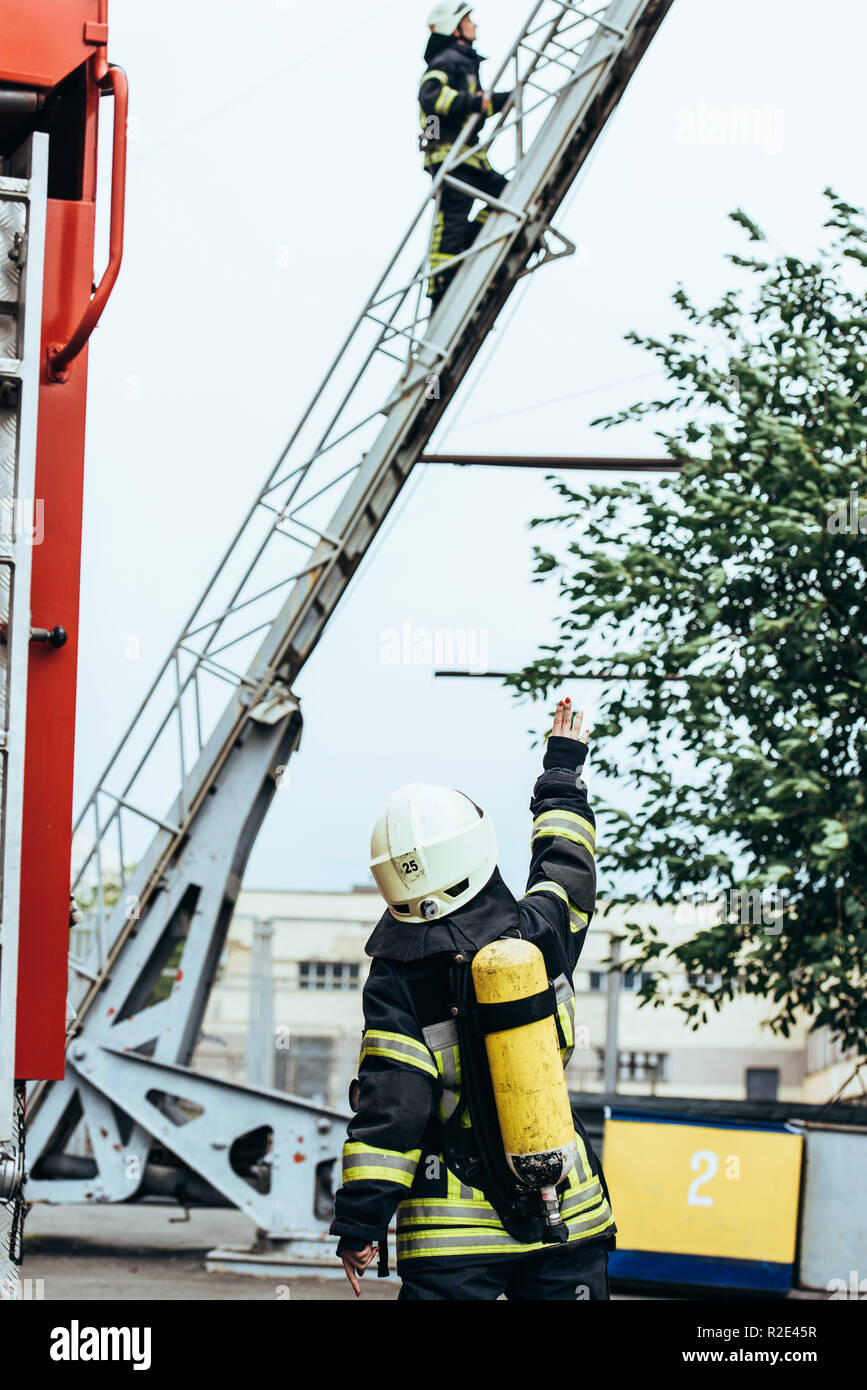back view of female firefighter with fire extinguisher on back ...