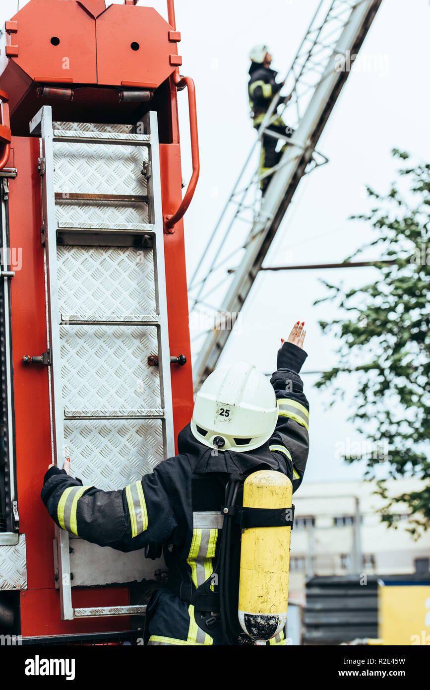 back view of female firefighter with fire extinguisher on back ...
