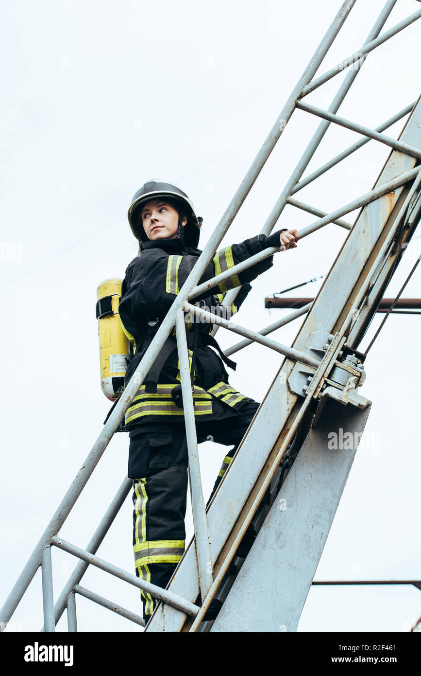 female firefighter in protective uniform and helmet with fire ...