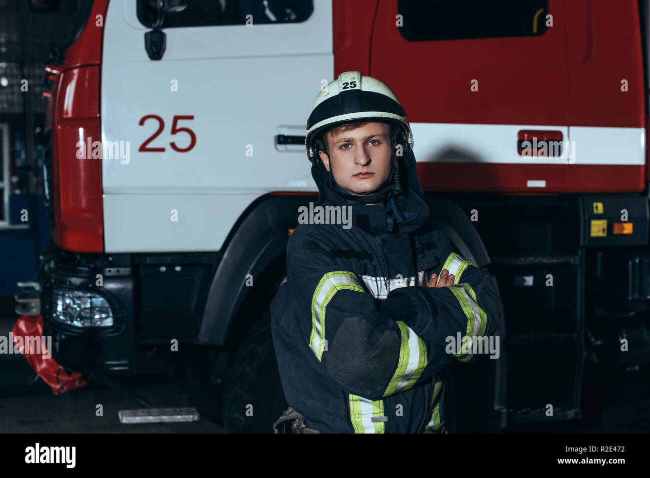 portrait of fireman in protective uniform and helmet with arms crossed ...