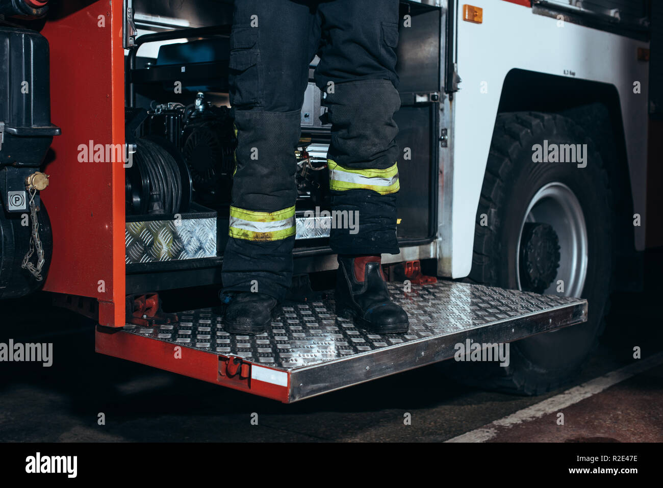 partial view of firefighter in fireproof uniform standing on truck at ...