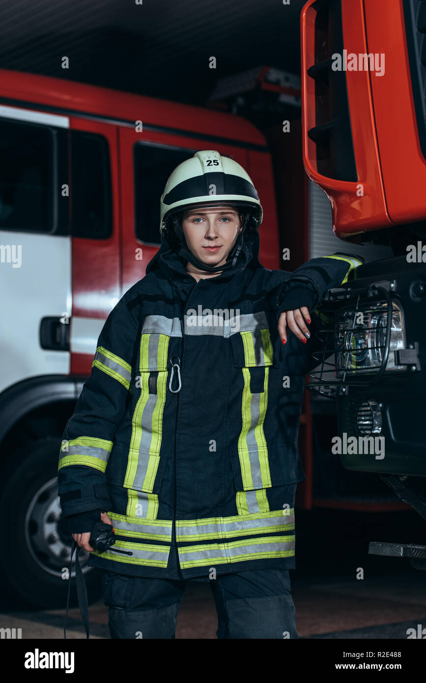 portrait of female firefighter in protective uniform with portable ...