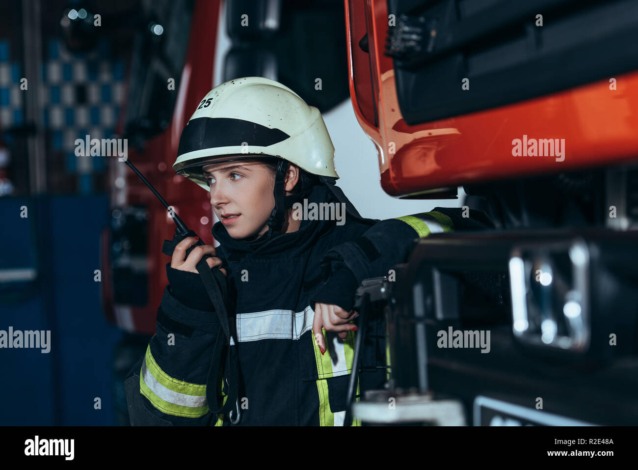 portrait of female firefighter in protective uniform talking into ...