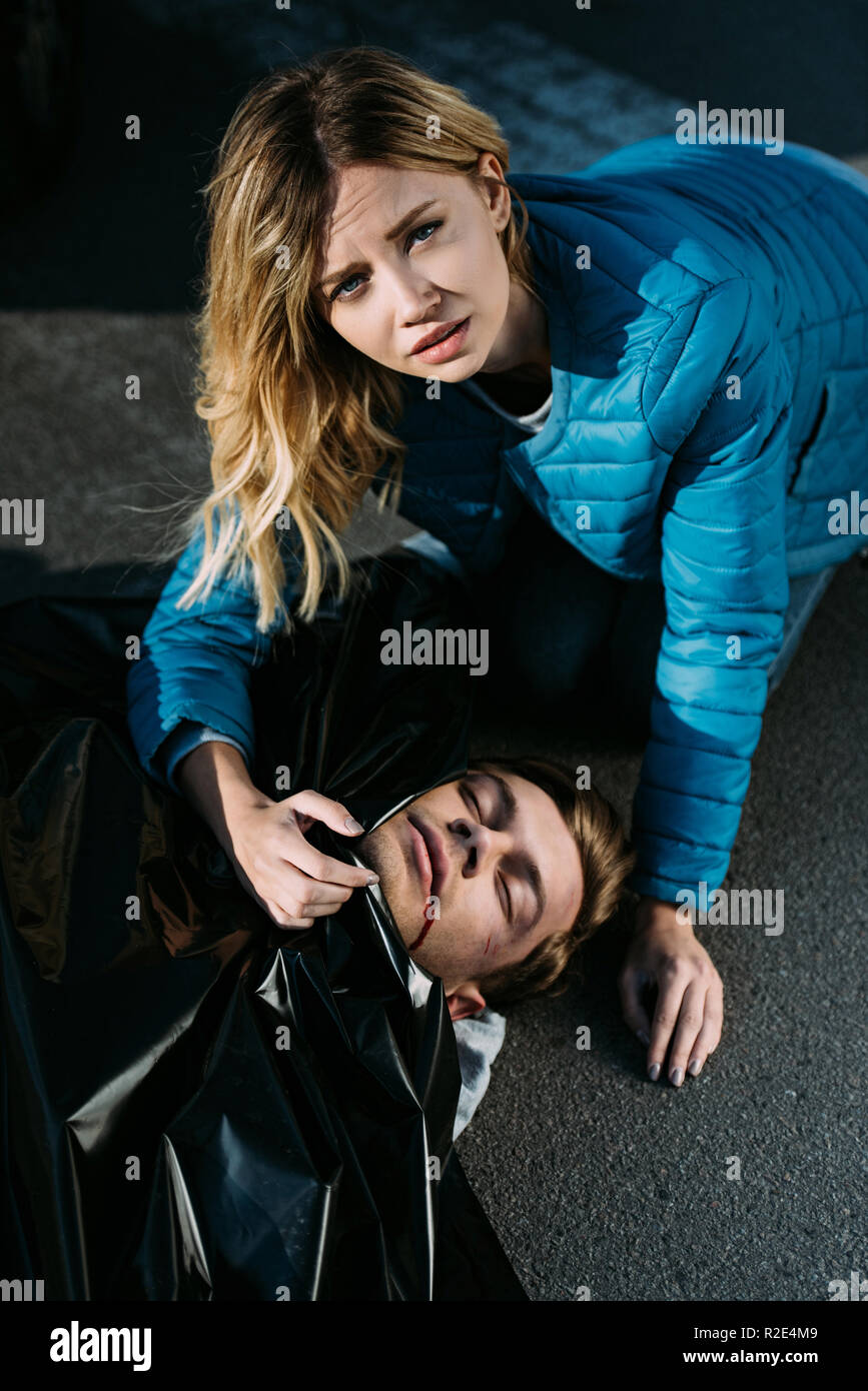 high angle view of young woman crying about dead body and looking at ...