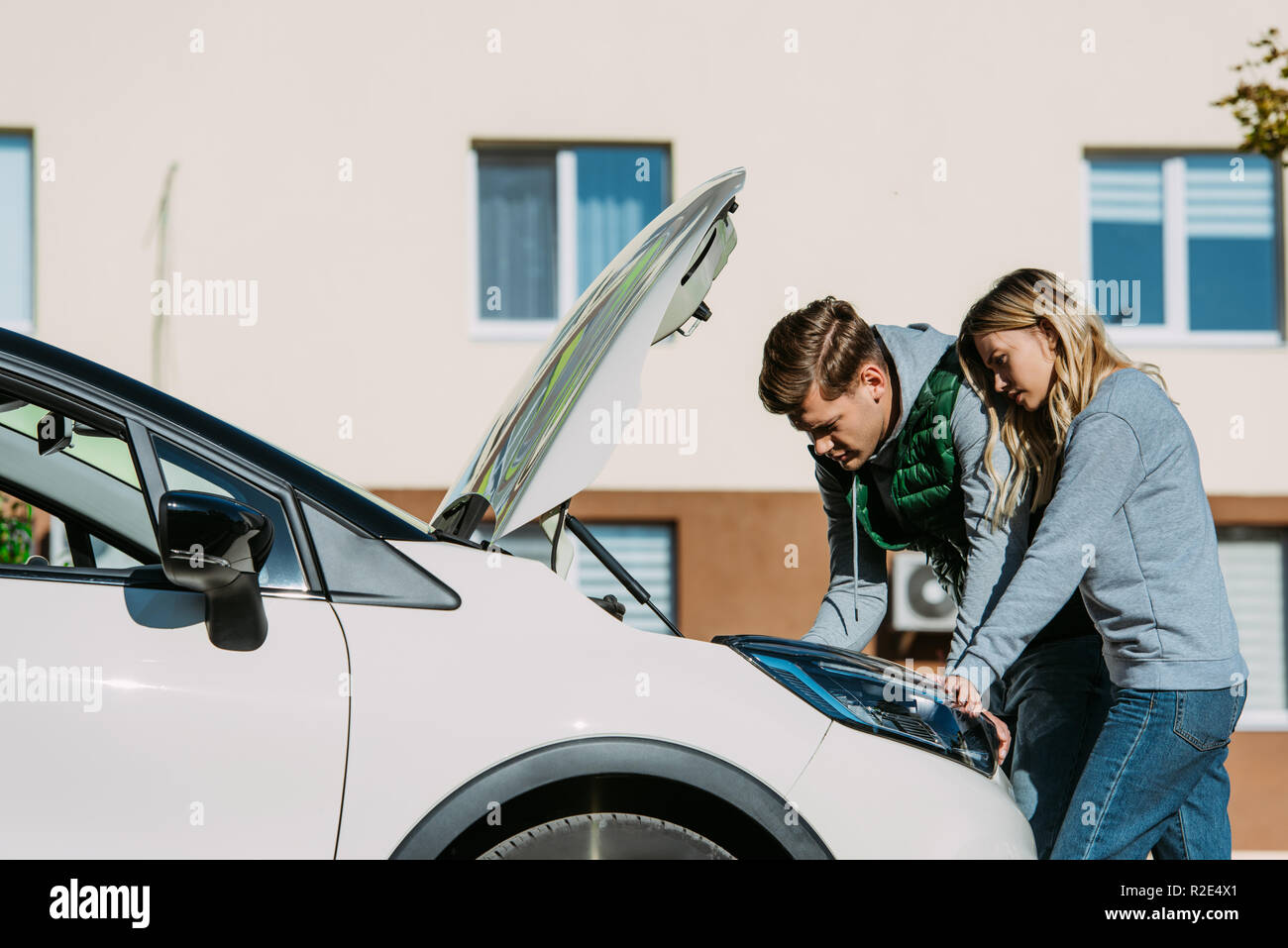 young couple repairing broken car on street Stock Photo - Alamy
