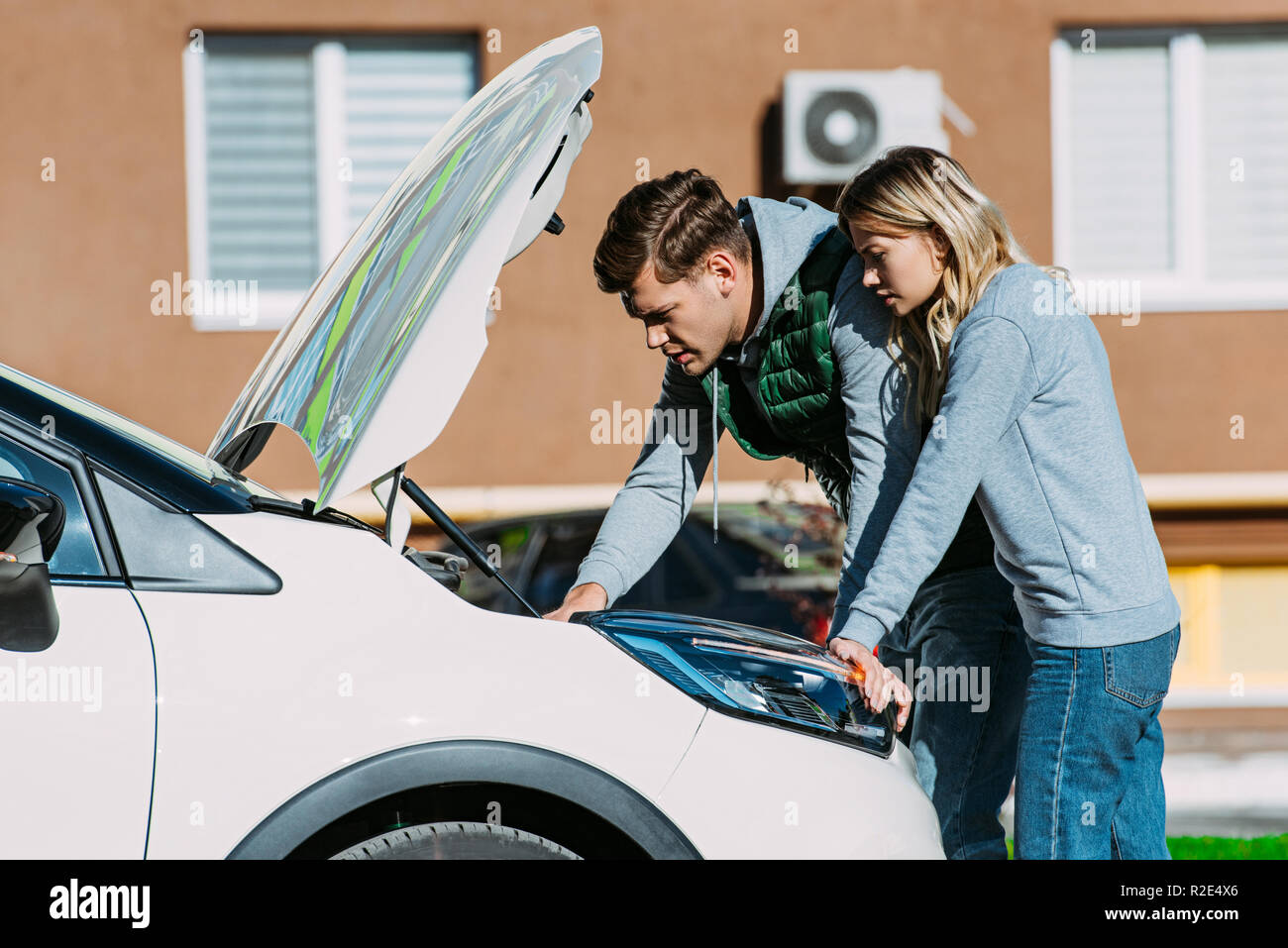 side view of young couple fixing broken car on street Stock Photo - Alamy