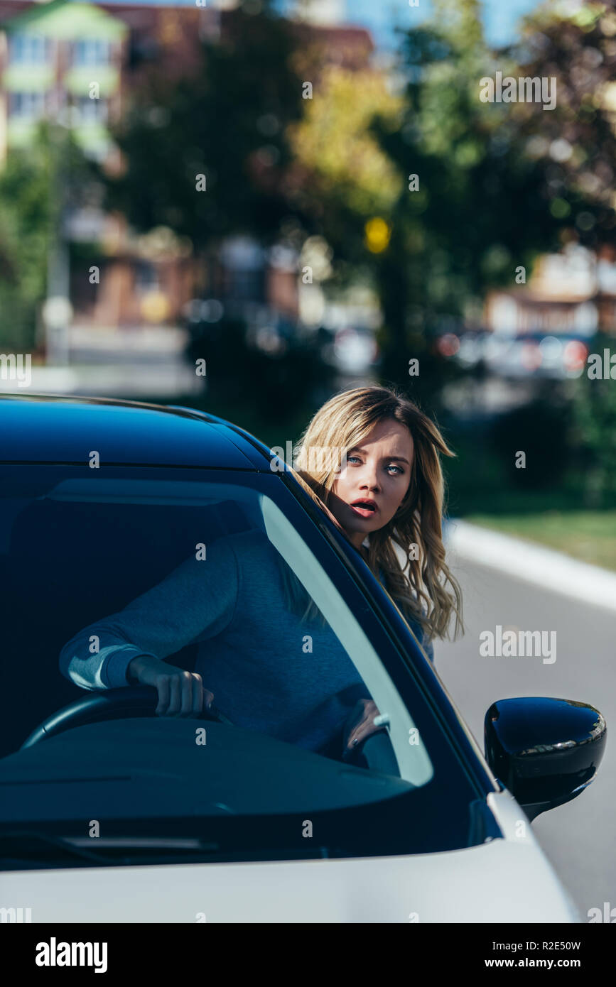 young shocked woman leaning out car window while driving car Stock ...