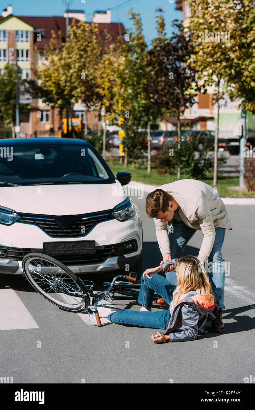 car driver helping injured young woman to get up after car accident on ...