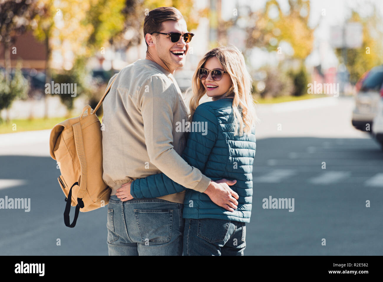 back view of happy couple hugging while walking on street in new city ...