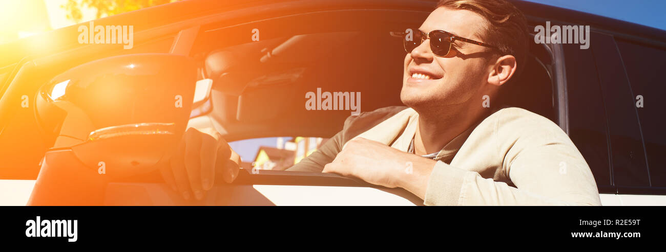 smiling young man leaning out car window of driving automobile Stock ...