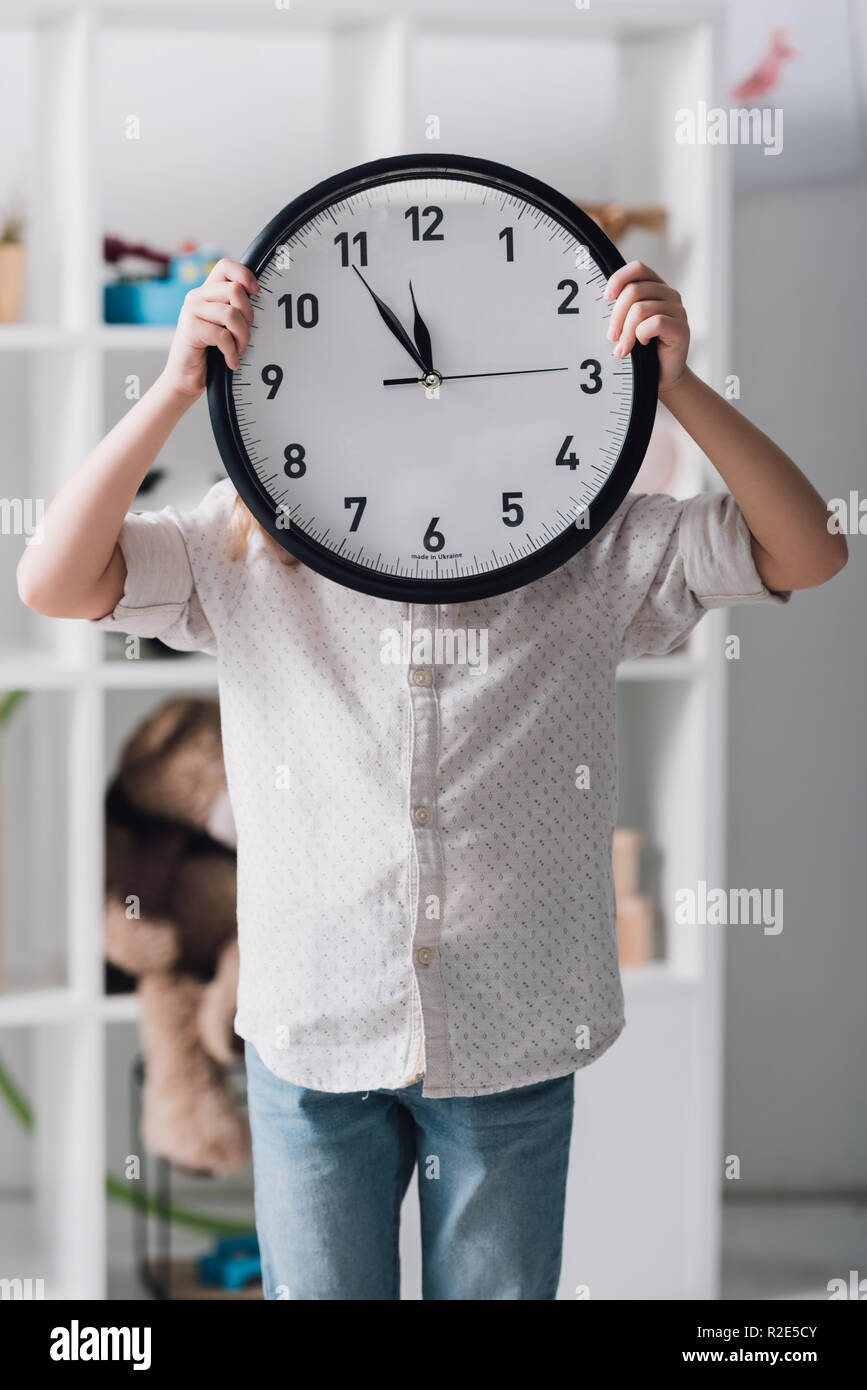 little child covering face with big clock Stock Photo - Alamy
