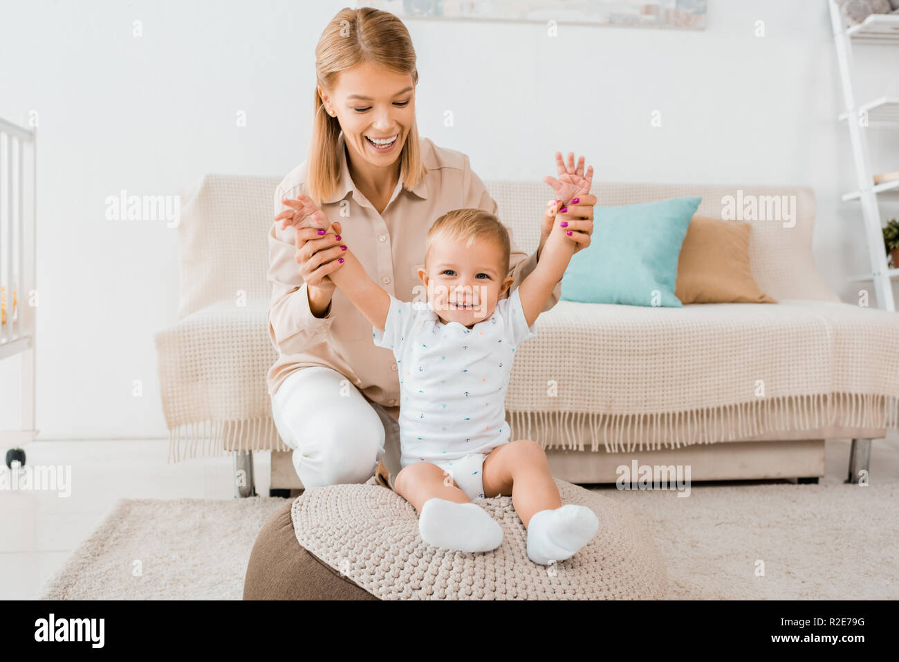 adorable toddler raising hands up with mother in nursery room Stock ...