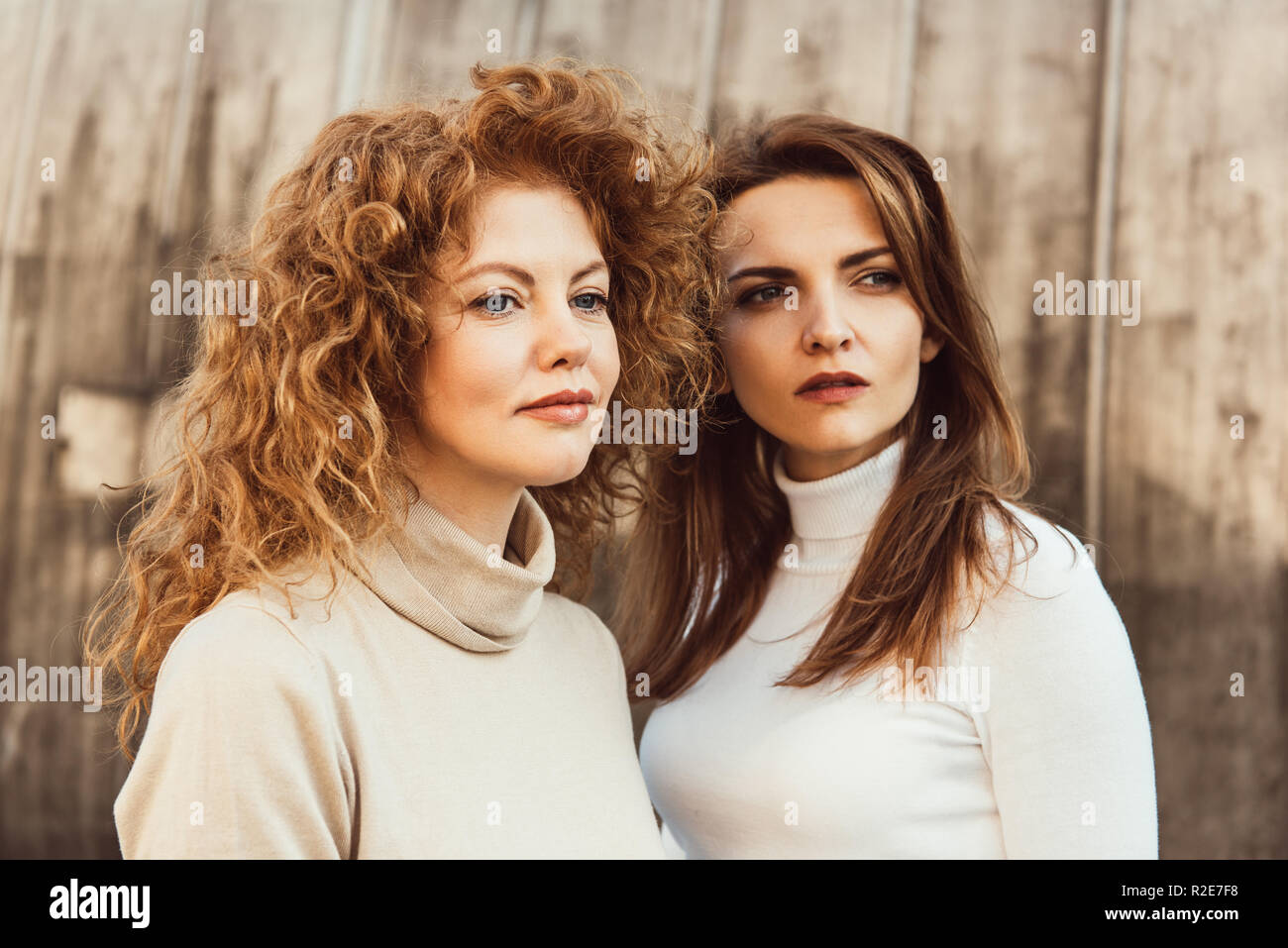 portrait of pretty female friends in turtle necks looking away at urban ...