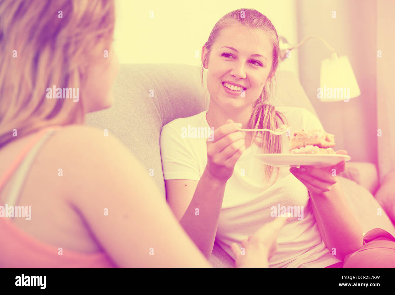 Positive women sitting on the sofa with plate of cake indoors Stock ...