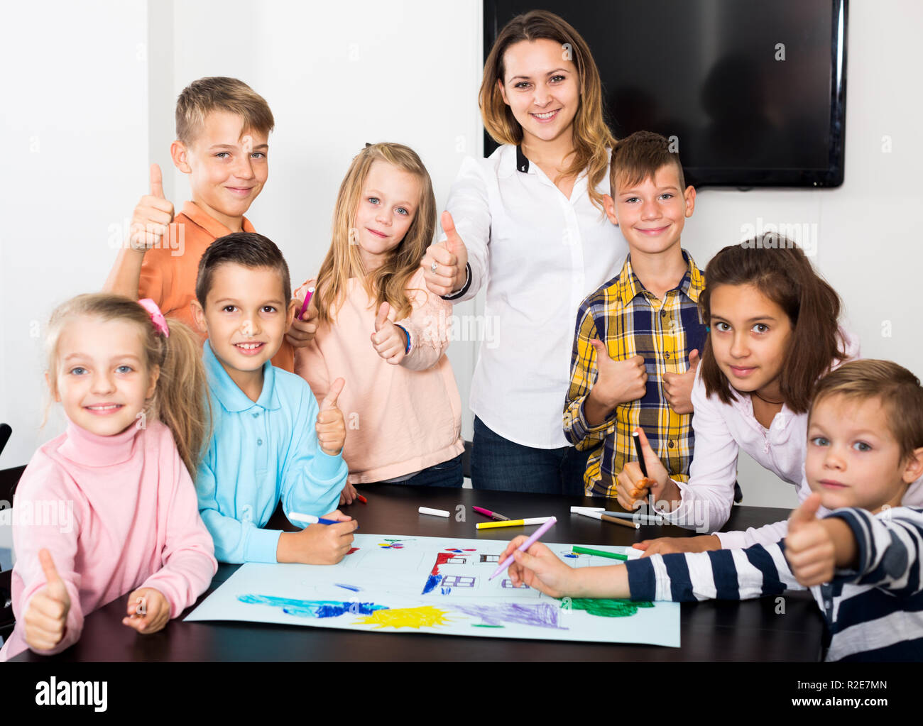 Portrait happy team of elementary age children drawing on one sheet ...