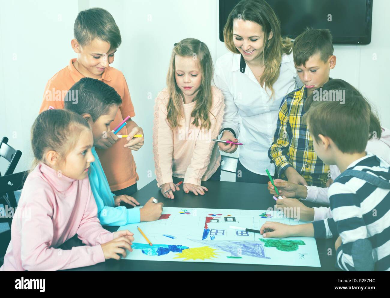 Smiling children with teacher drawing together in classroom Stock Photo ...