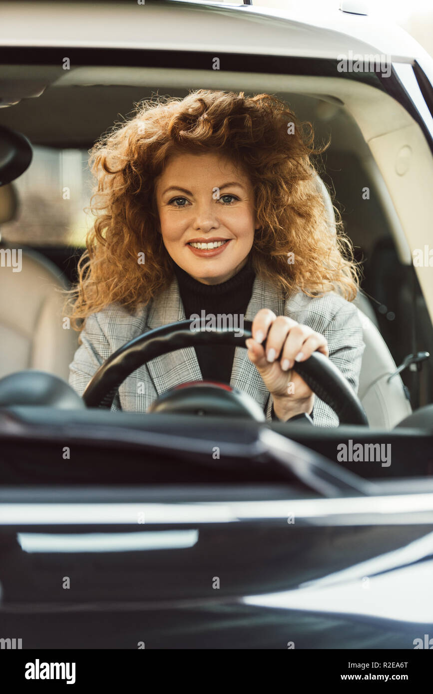 smiling attractive curly redhead woman driving car Stock Photo - Alamy