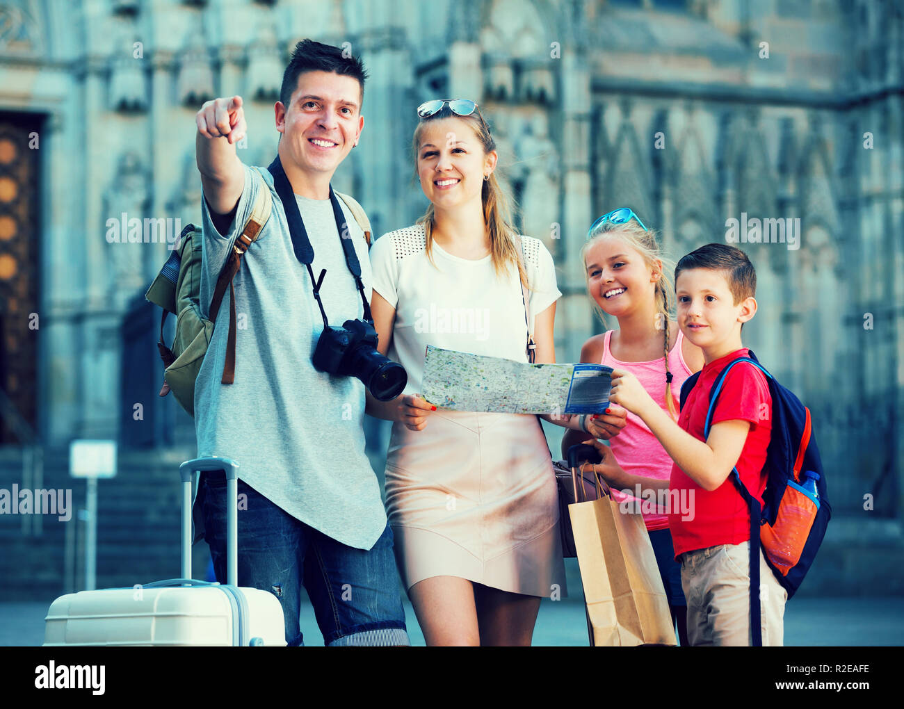 Positive family of tourists with two kids looking for destination with ...