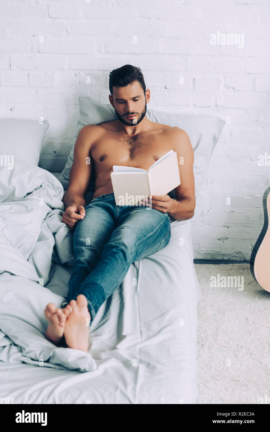 high angle view of shirtless muscular man reading book during morning ...