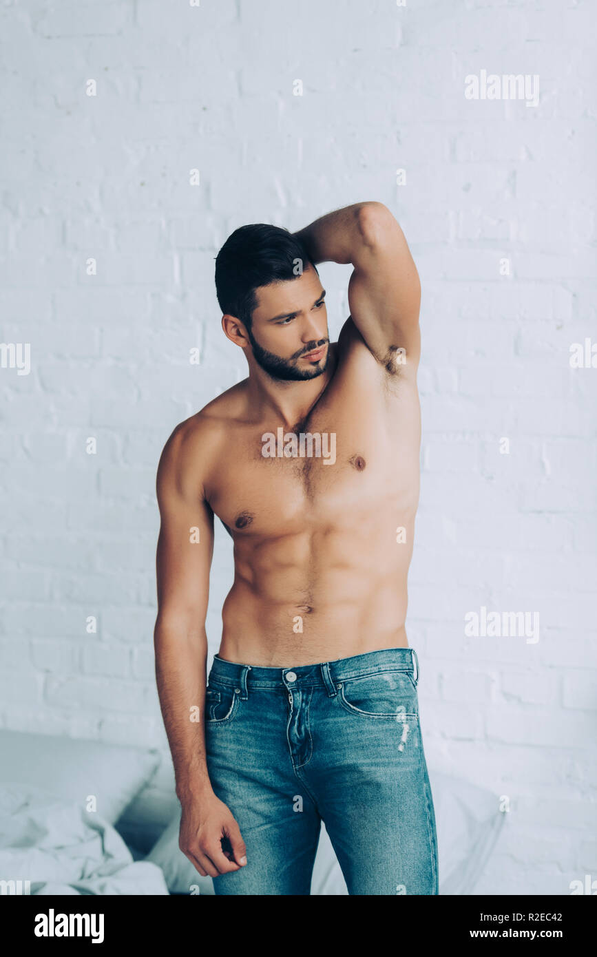 handsome shirtless man with muscular torso posing in bedroom at home ...