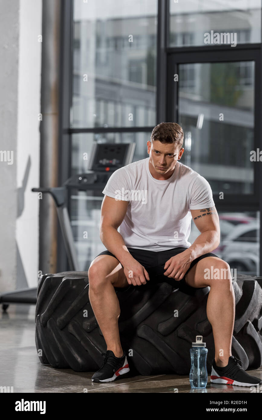 tired handsome athletic bodybuilder sitting on tire in gym Stock Photo ...